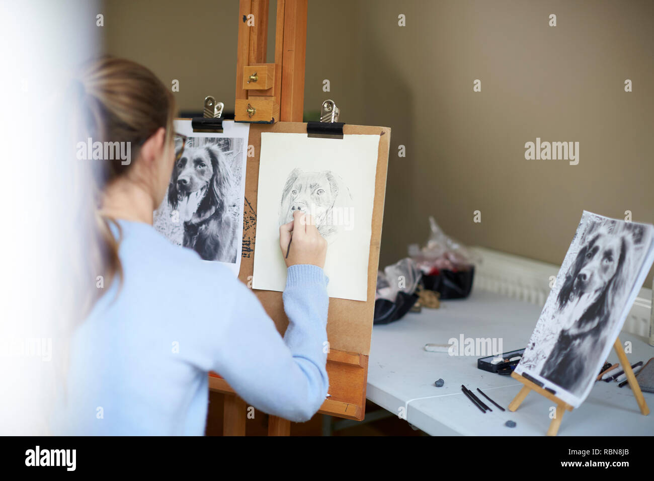 Rear View Of Female Teenage Artist Sitting At Easel Drawing Picture Of ...