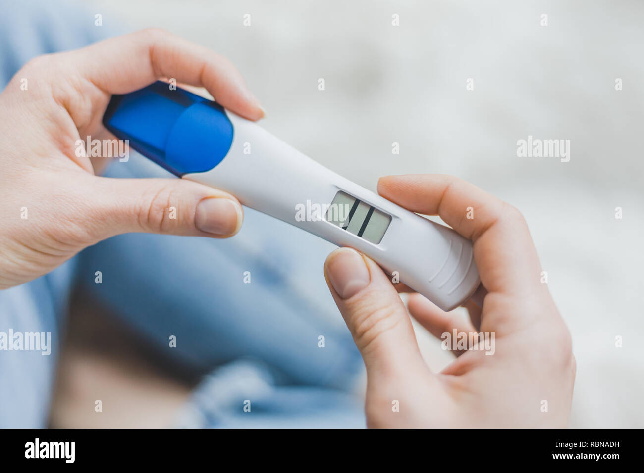 Young woman or girl looking on positive pregnancy test with two stripes ...