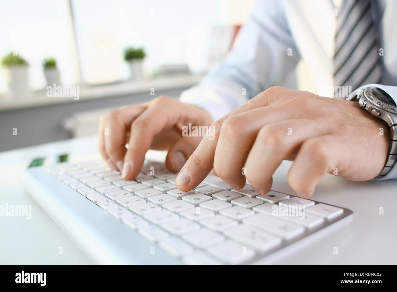 Male arms in suit typing on silver keyboard Stock Photo - Alamy