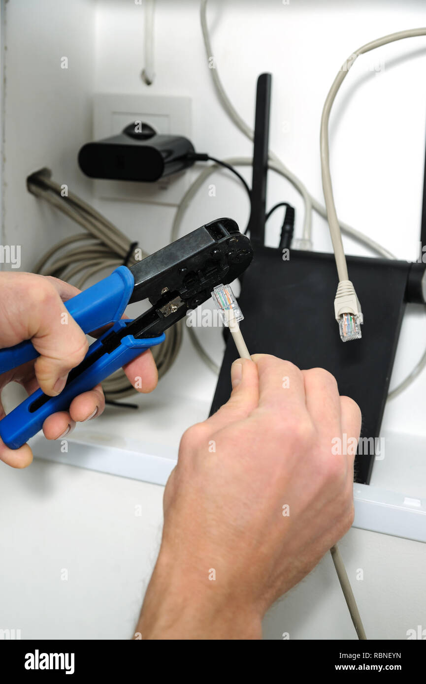 Connecting wi-fi router to the Internet. Hands man fixing cable ...