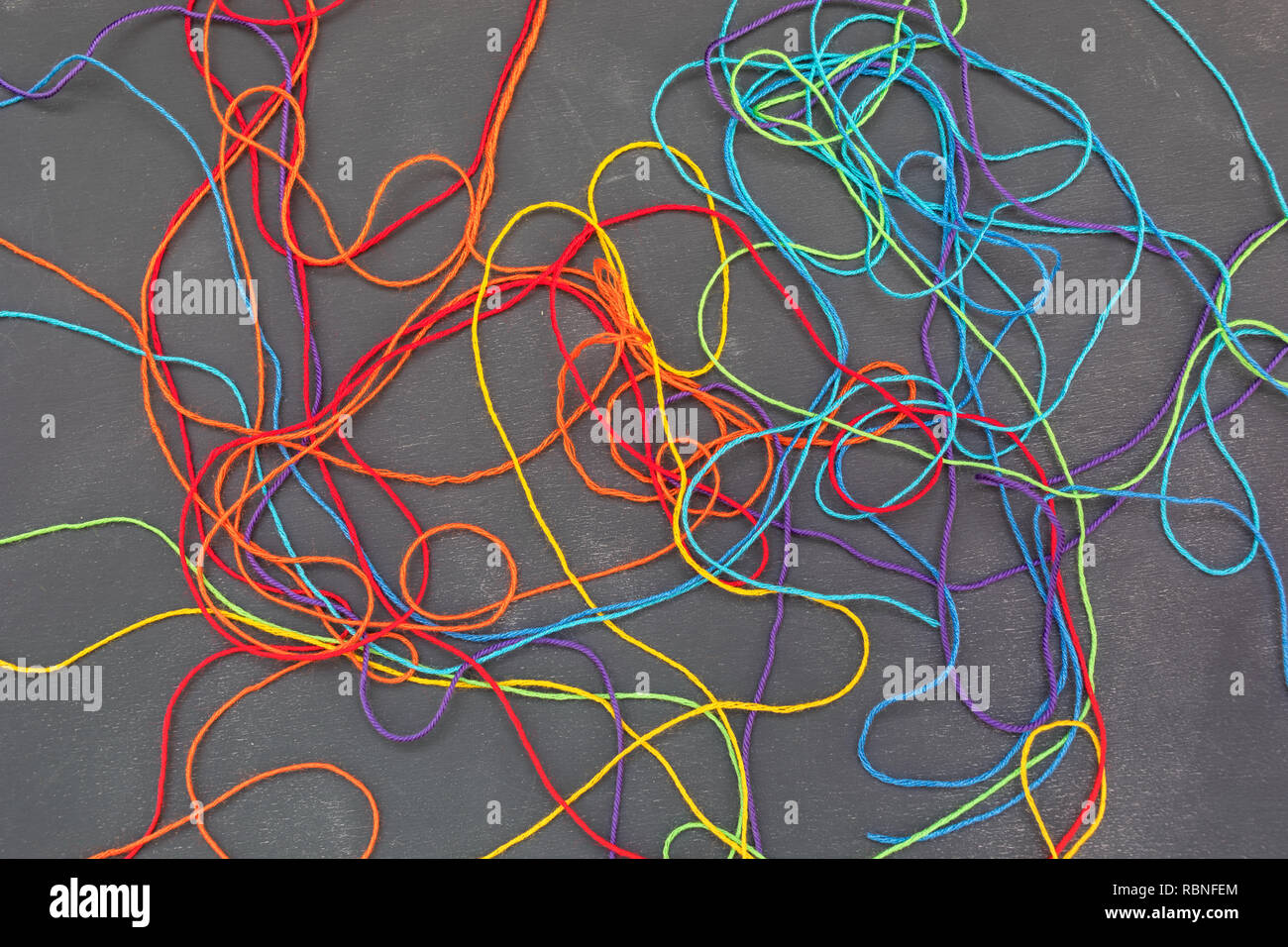 Pattern of bright multicolored threads on dark grey background ...