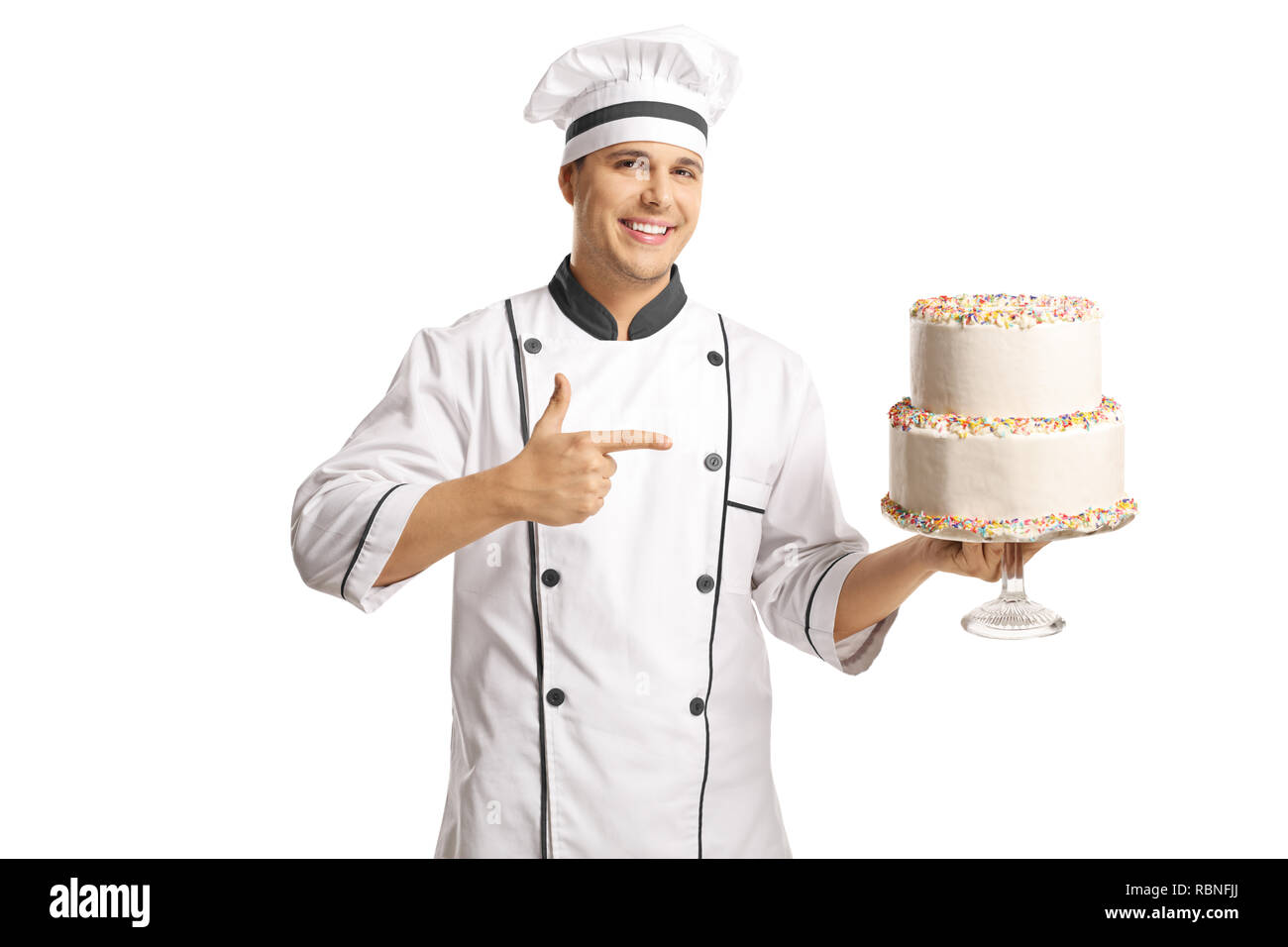 Cheerful male chef holding a cake and pointing at it isolated on white ...
