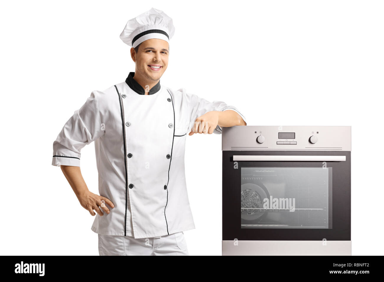 Smiling young male chef standing next to an oven isolated on white ...