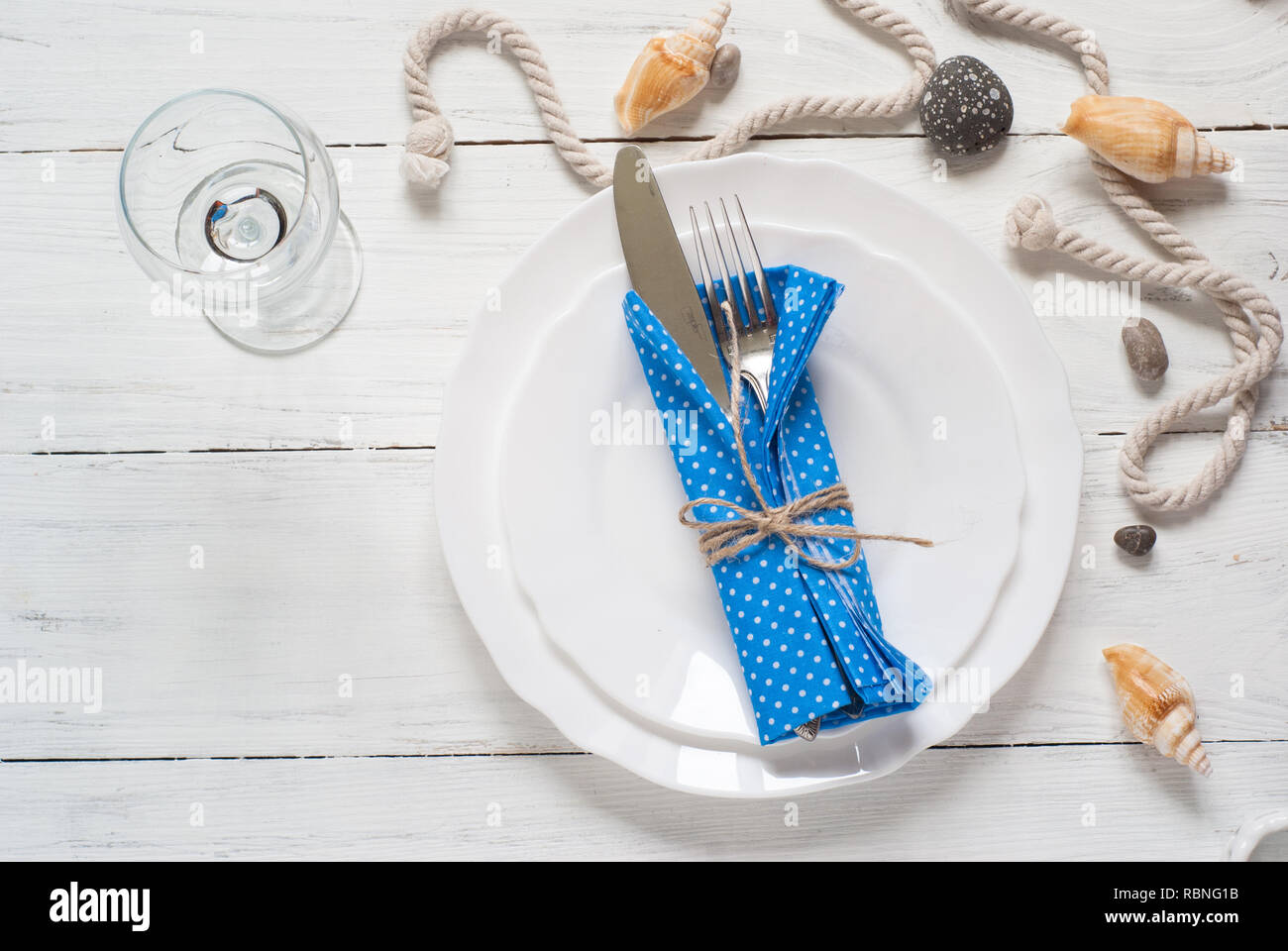 Marine table setting with white dishes and sea decorations at white ...