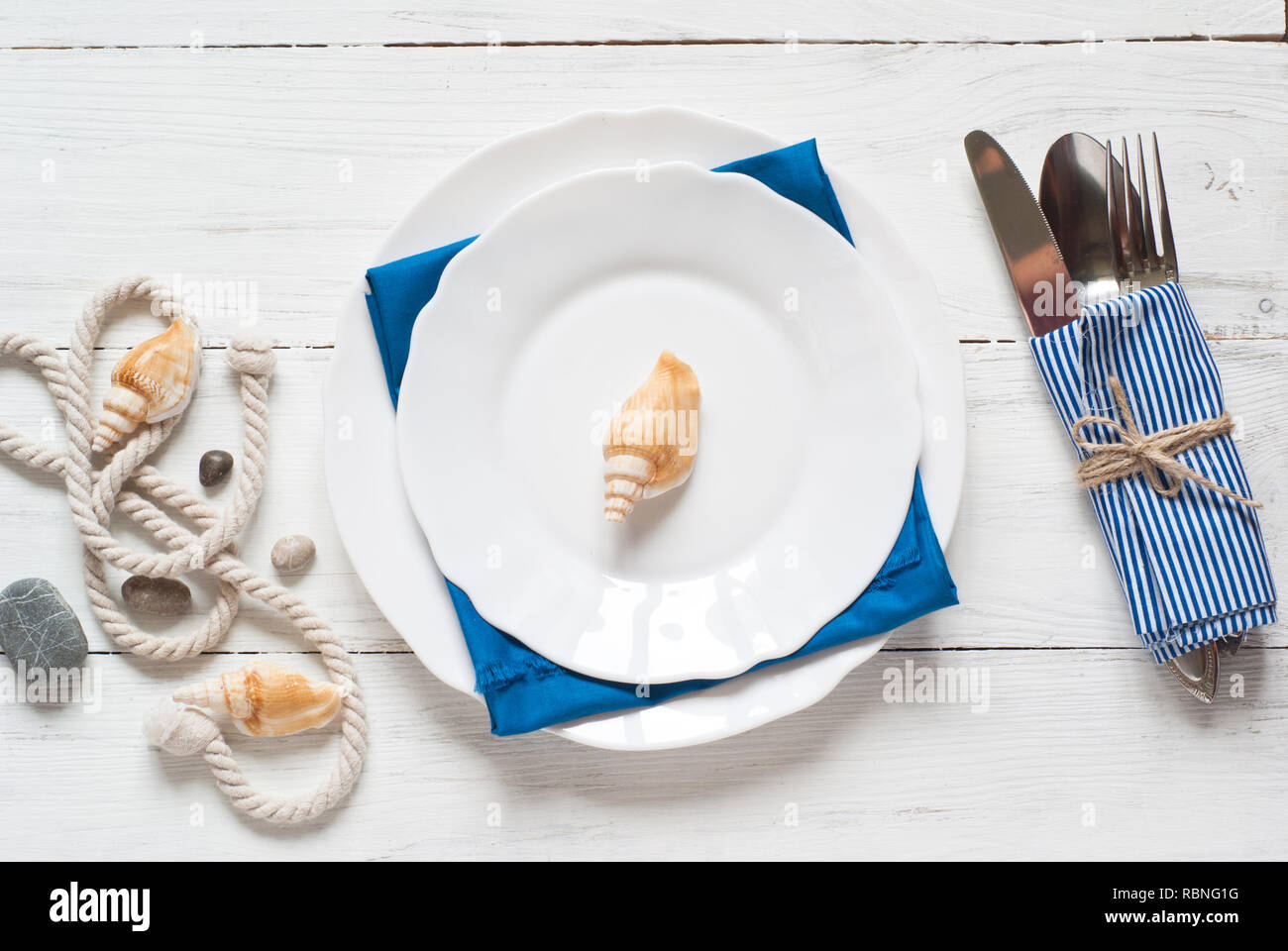 Marine table setting with white dishes and sea decorations at white ...