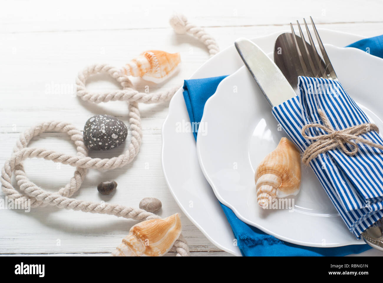 Marine table setting with white dishes and sea decorations at white ...