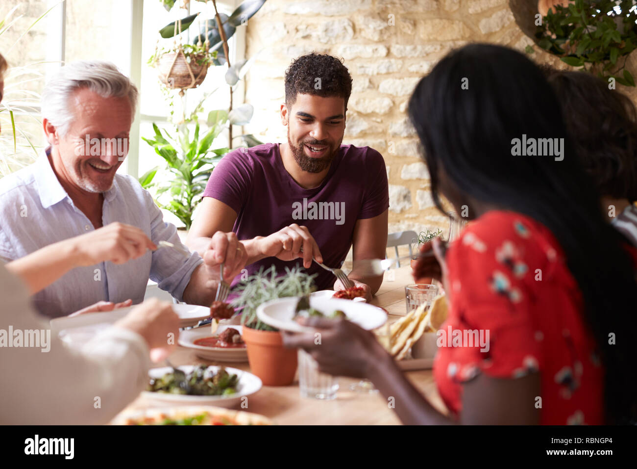 Smiling friends eating together at a table in a cafe Stock Photo - Alamy
