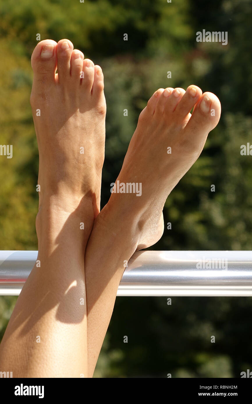 Woman holds her feet up in the sun, vertical full frame Stock Photo - Alamy