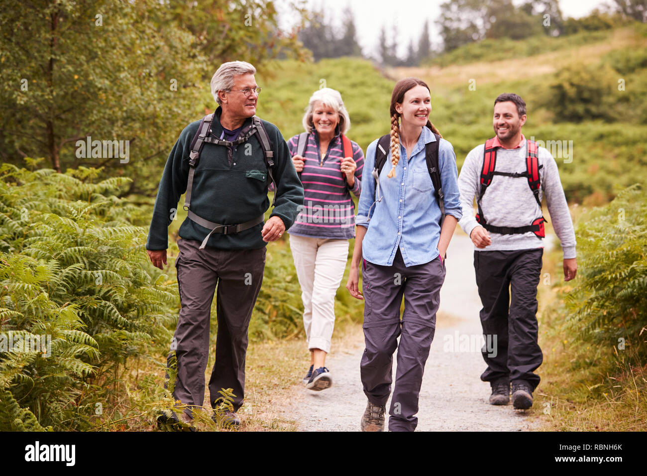 Two mixed age couples walking on a countryside path during family ...