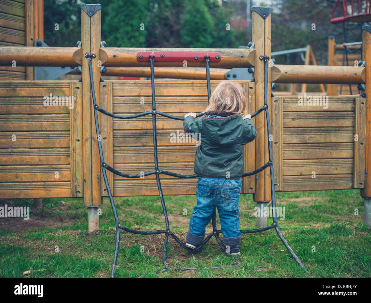A little toddler is climbing a rope in the playground Stock Photo - Alamy