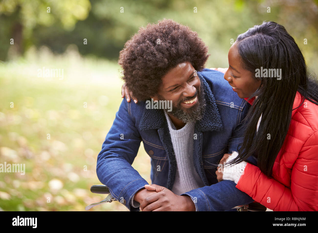Black couple embracing and looking at each other smiling in a park ...