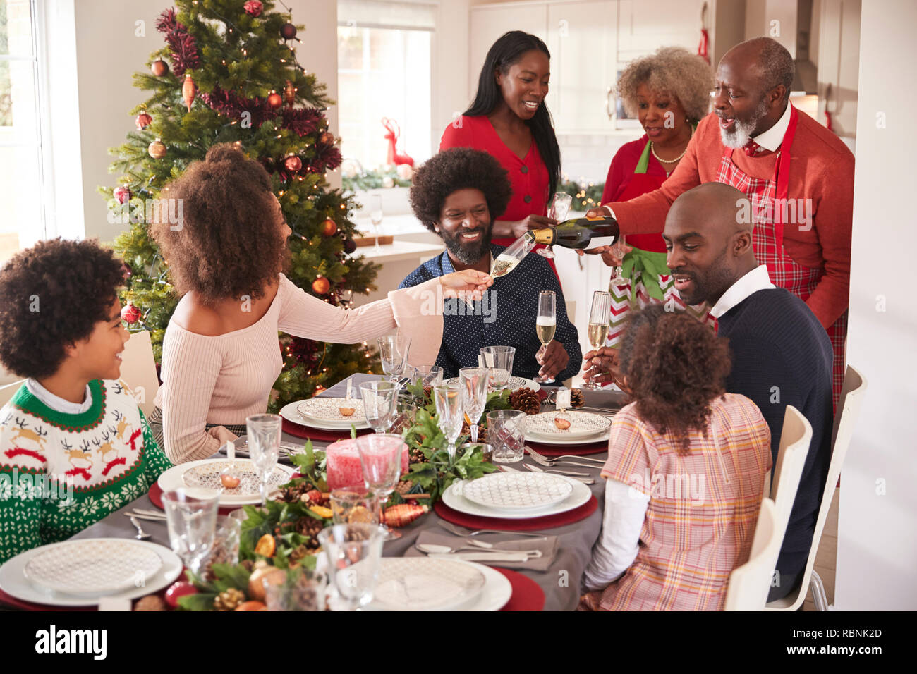 Grandfather pouring champagne at the dinner table during a multi ...