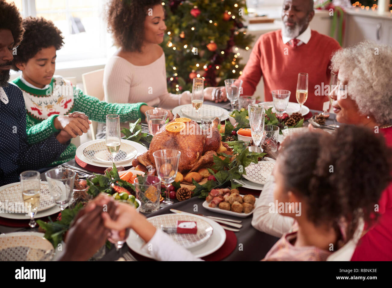 Multi generation mixed race family sitting at Christmas dinner table ...