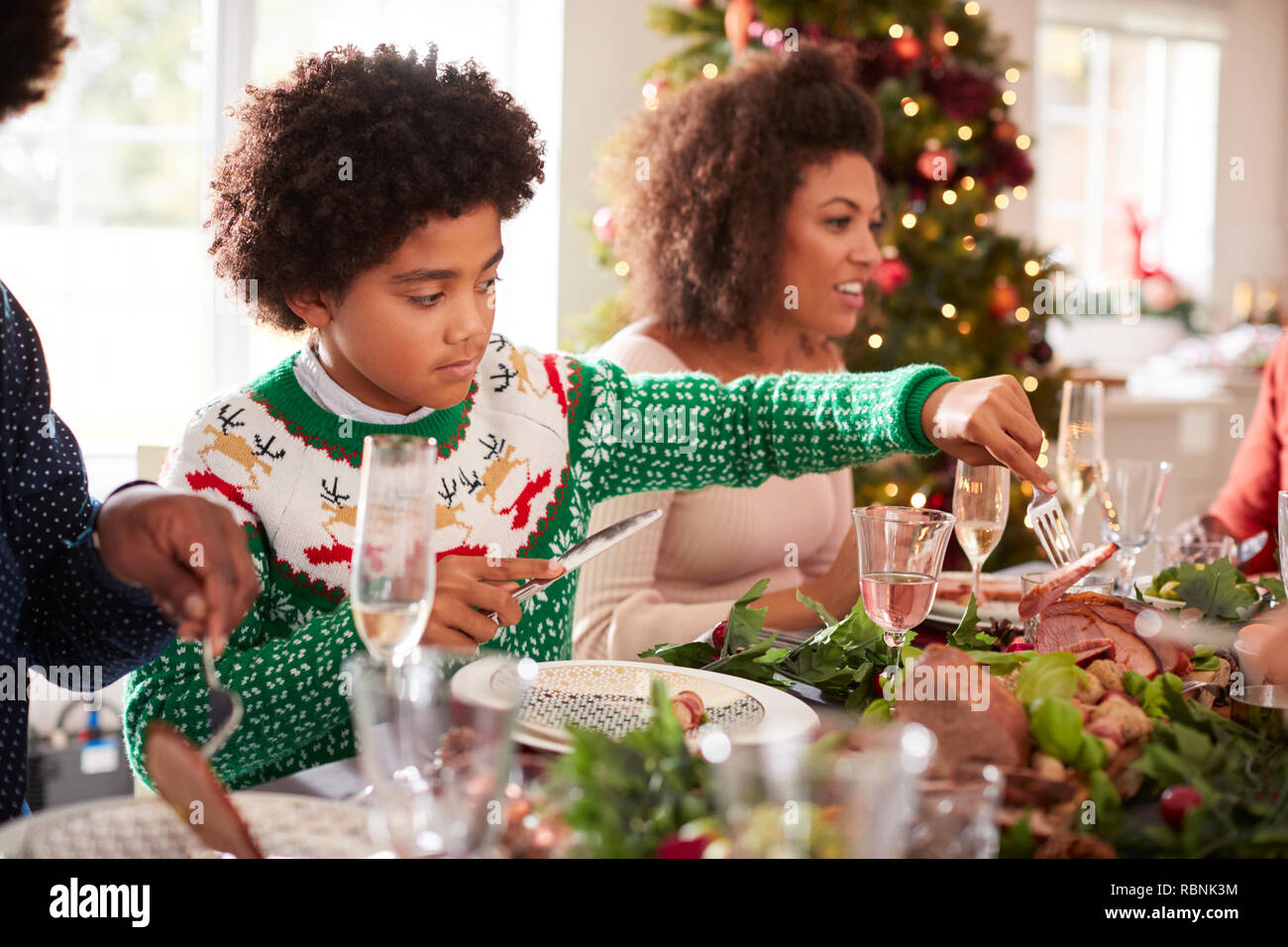 Tween black boy serving himself roast turkey sitting at the Christmas ...