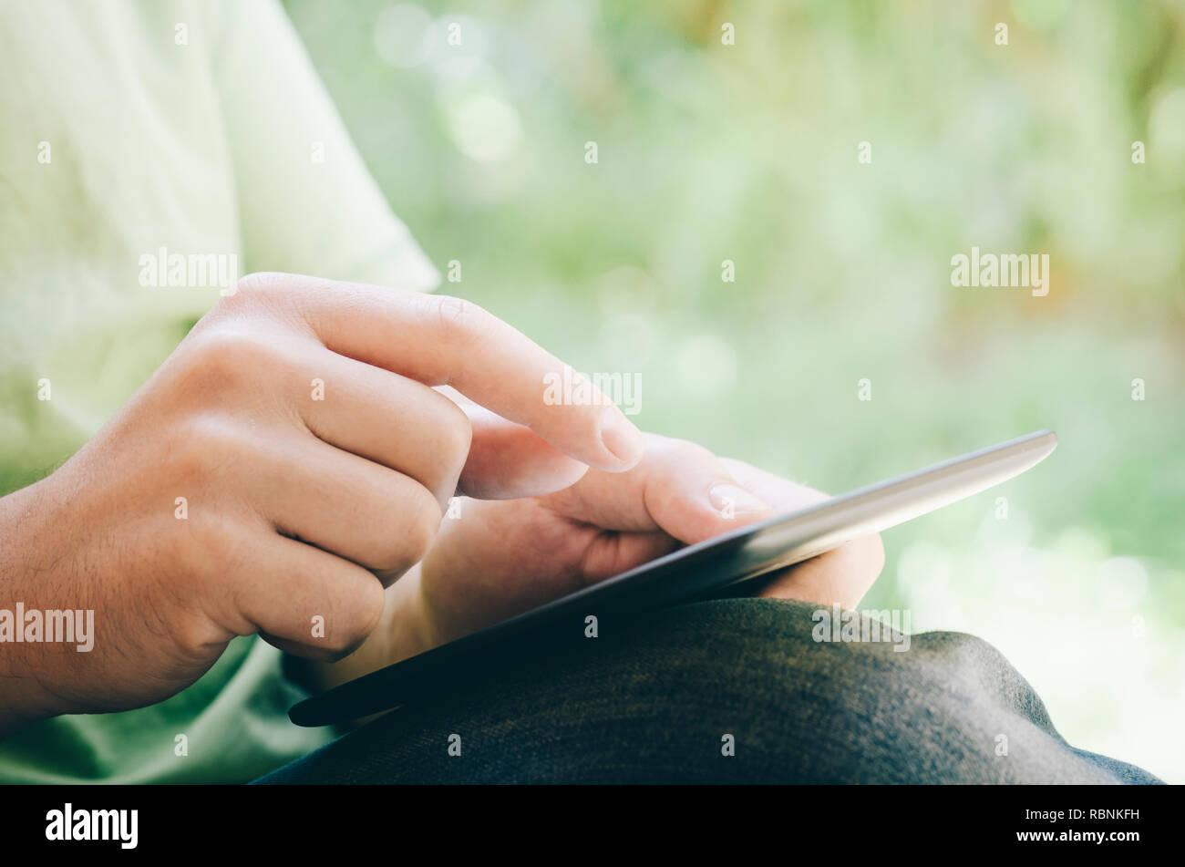 Closeup of hand holding computer tablet with green natural bokeh ...