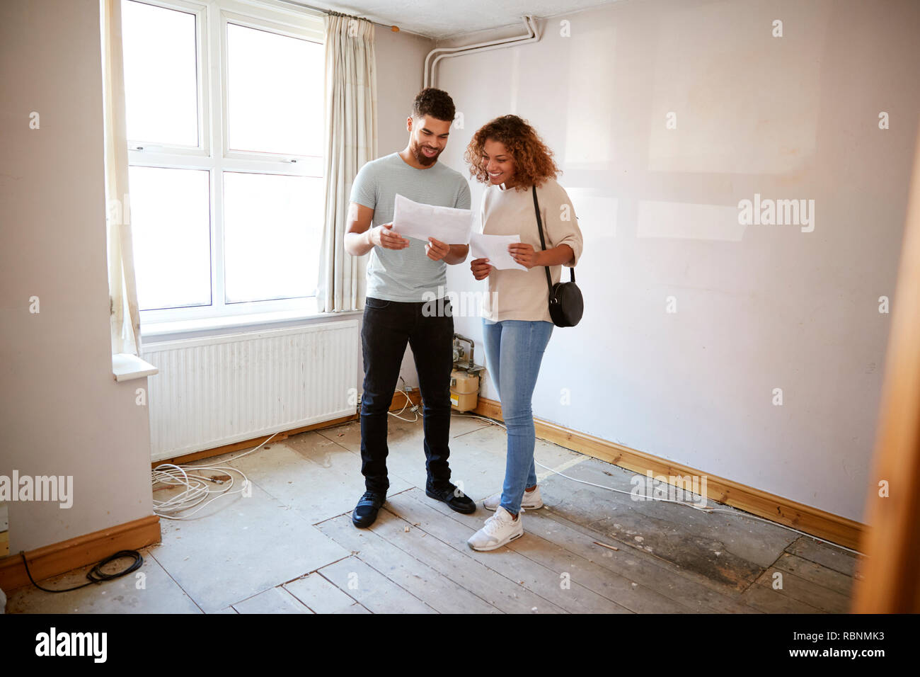 Couple Buying House For First Time Looking At House Survey In Room To ...