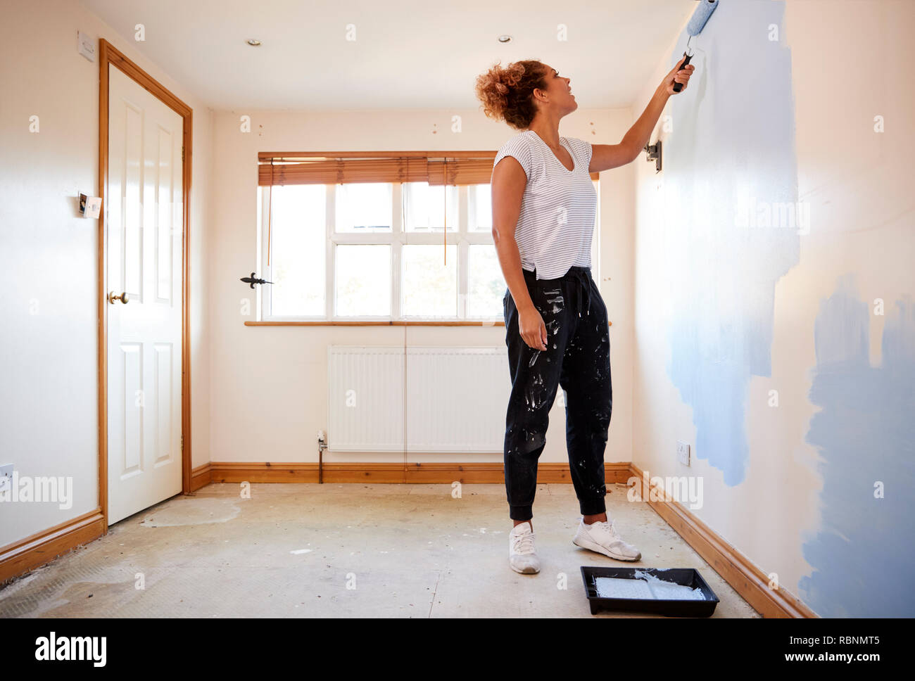 Woman Decorating Room In New Home Painting Wall Stock Photo - Alamy