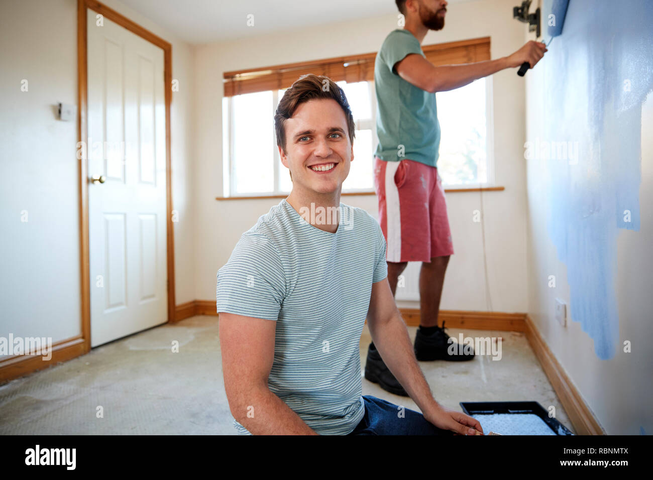 Portrait Of Two Men Decorating Room In New Home Painting Wall Together ...