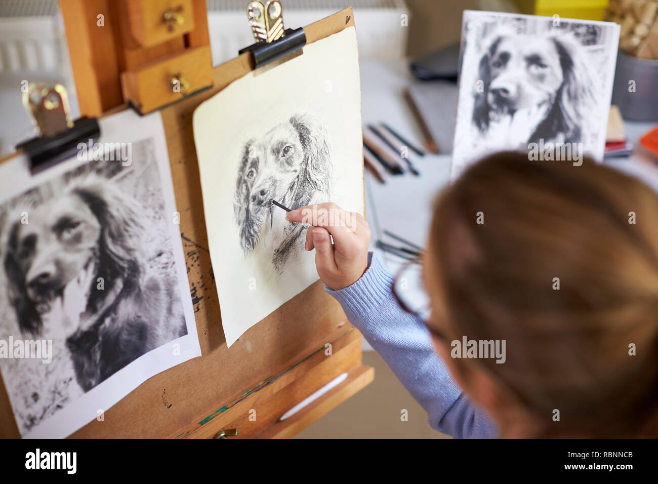 Rear View Of Female Teenage Artist Sitting At Easel Drawing Picture Of ...
