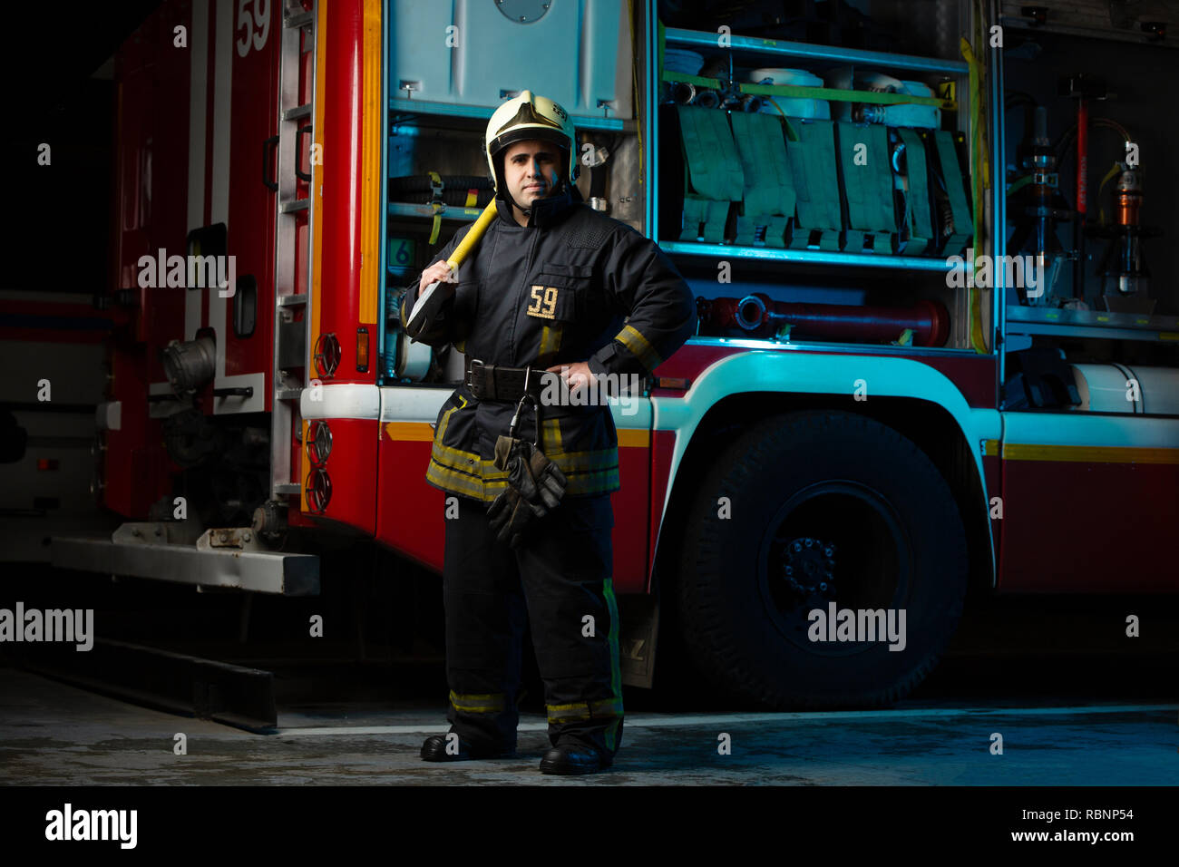 Full-length image of man firefighter with pick near fire truck at ...