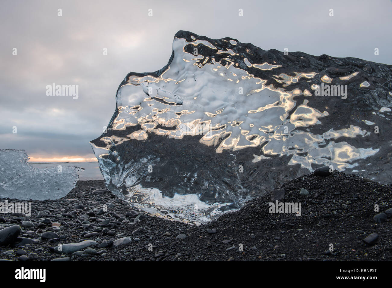 sun reflection in transparent iceberg on stony beach Stock Photo - Alamy