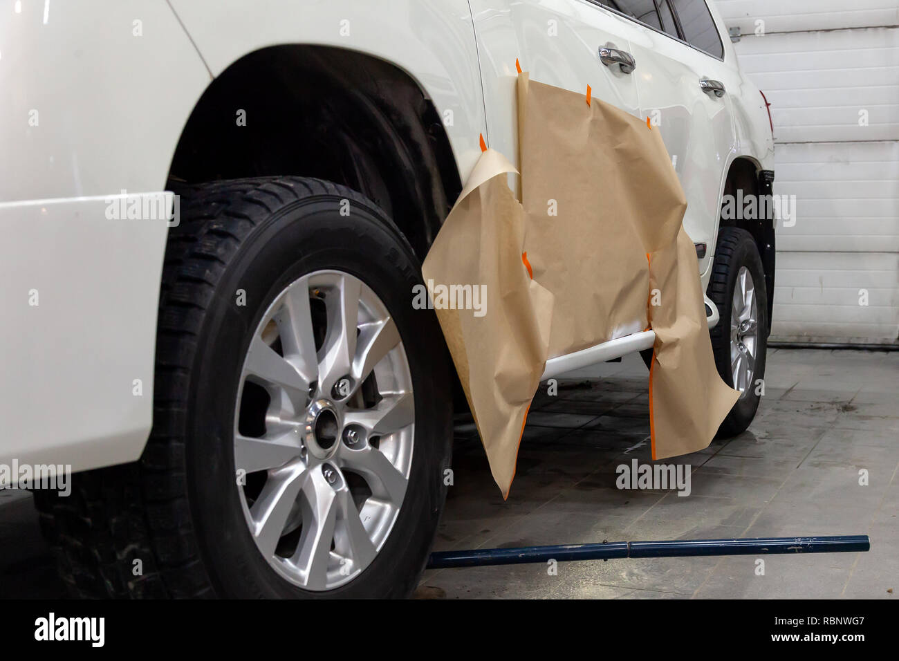 Partial painting of the side elements of the body of a white SUV car ...