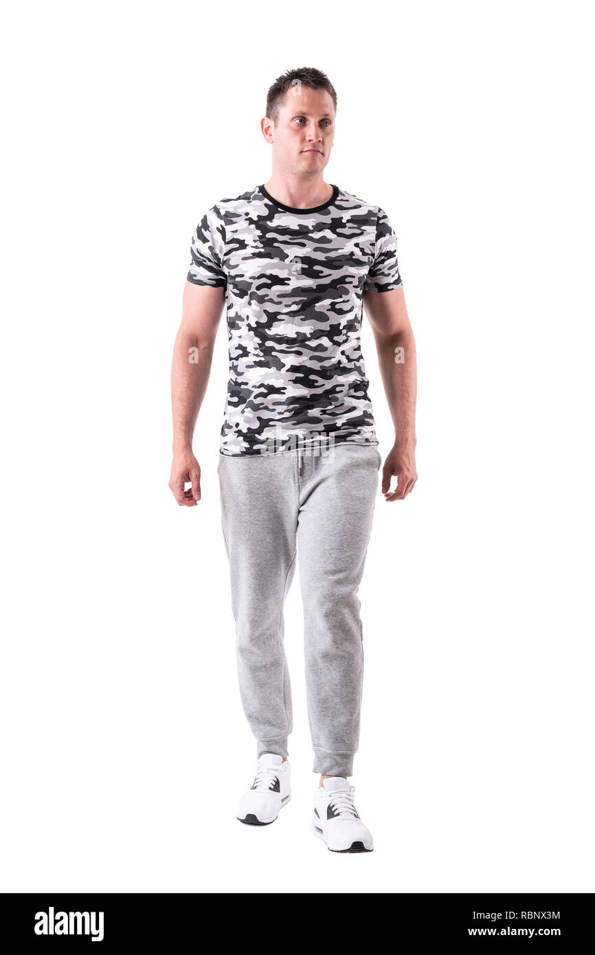 Serious confident fit man in sporty clothes walking and looking away ...