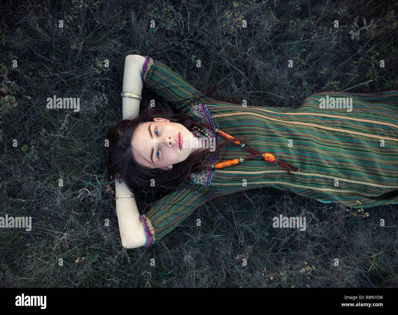 Beautiful hippie woman lying on grass relaxing on summer field ...