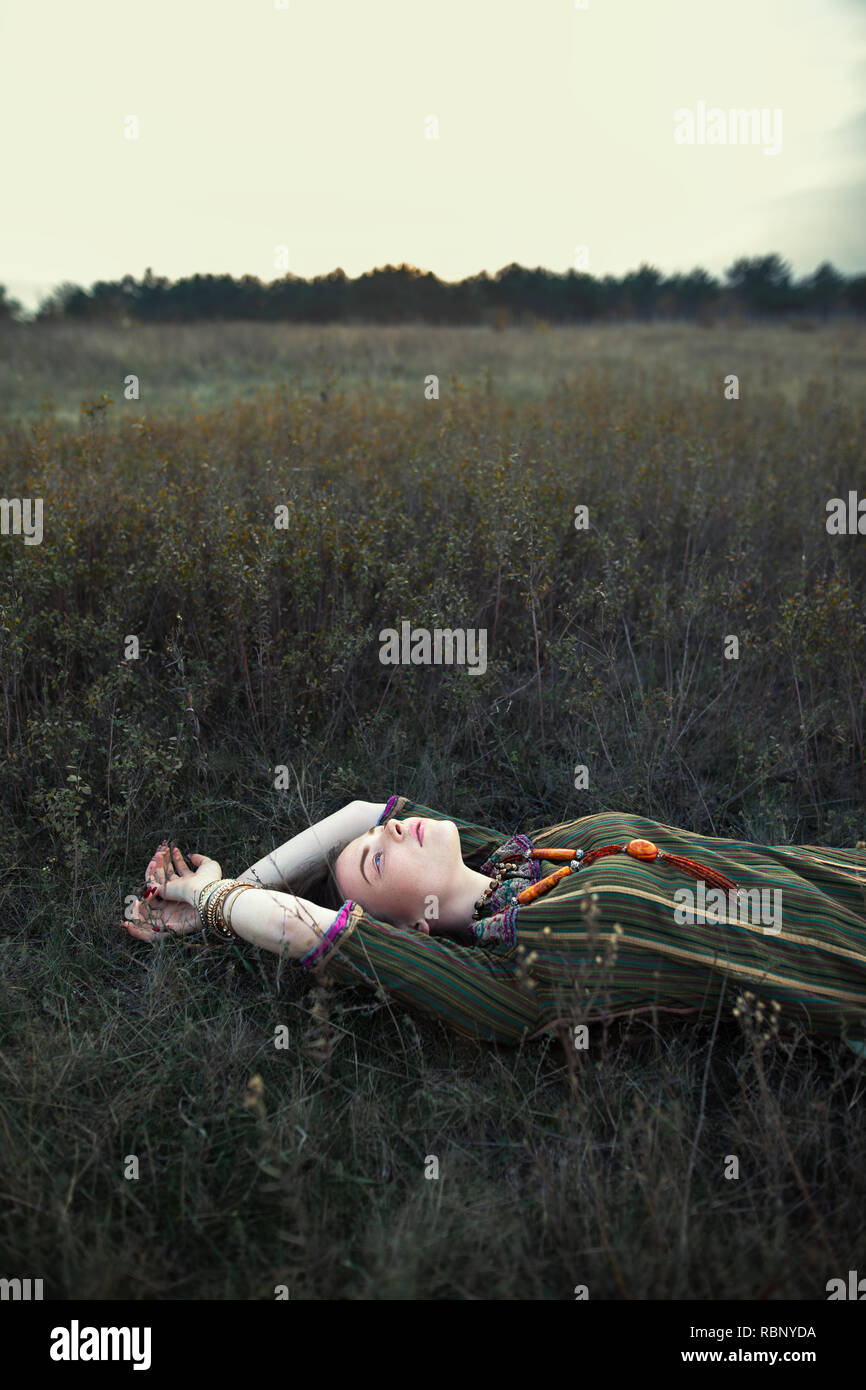 Beautiful hippie woman lying on grass relaxing on summer field ...