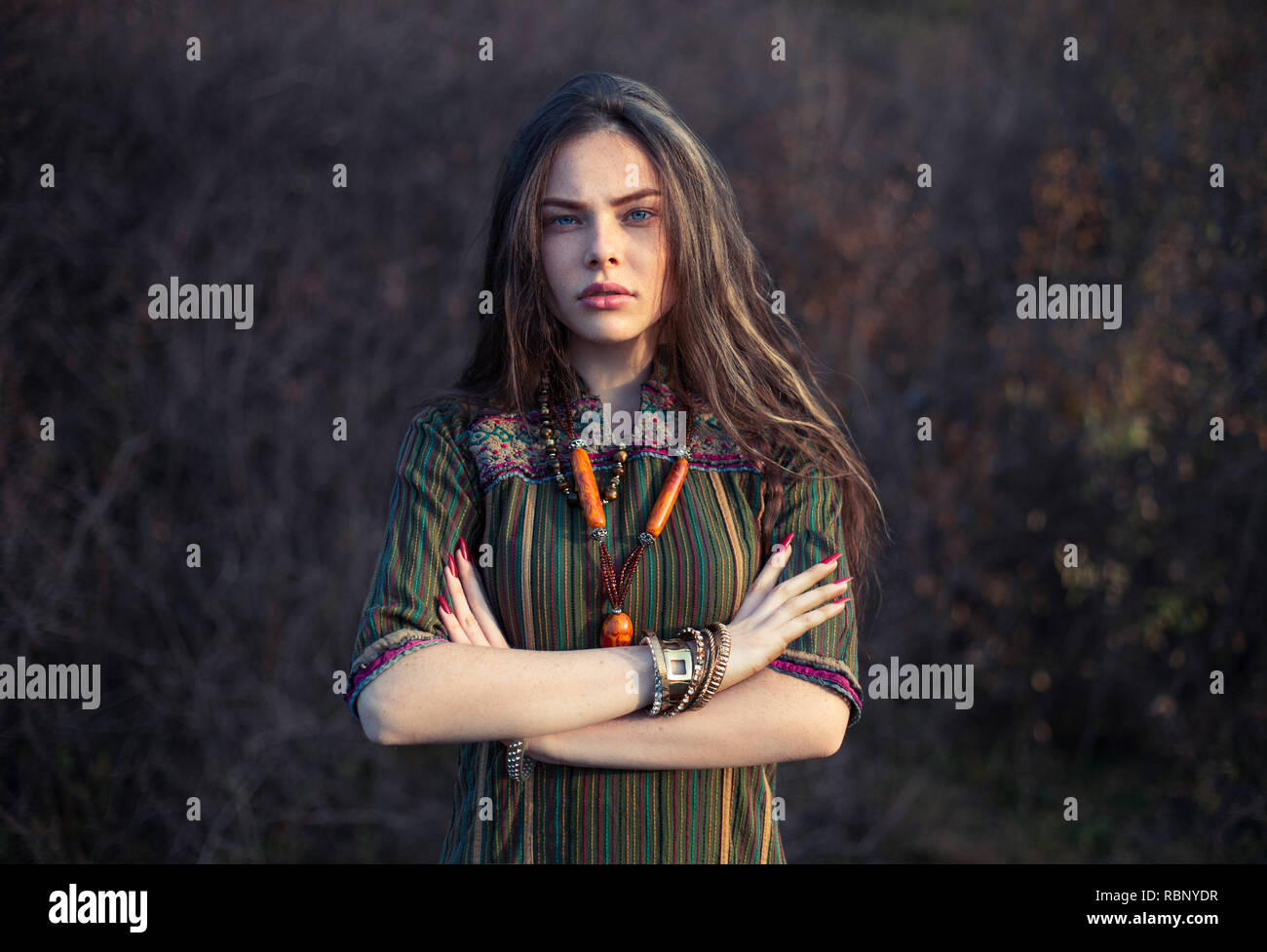 Portrait of young beautiful hippie girl on sunset outdoors. Crossed ...