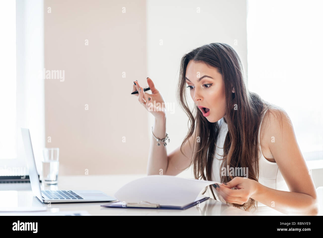 Shocked businesswoman reading paper at workplace in office. Business ...