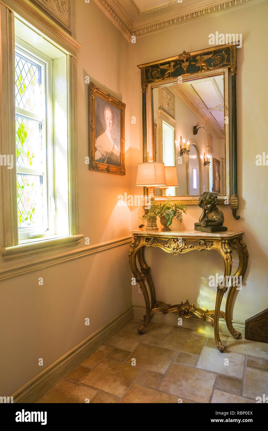 Antique wooden console with statue, illuminated lamp in main entryway ...