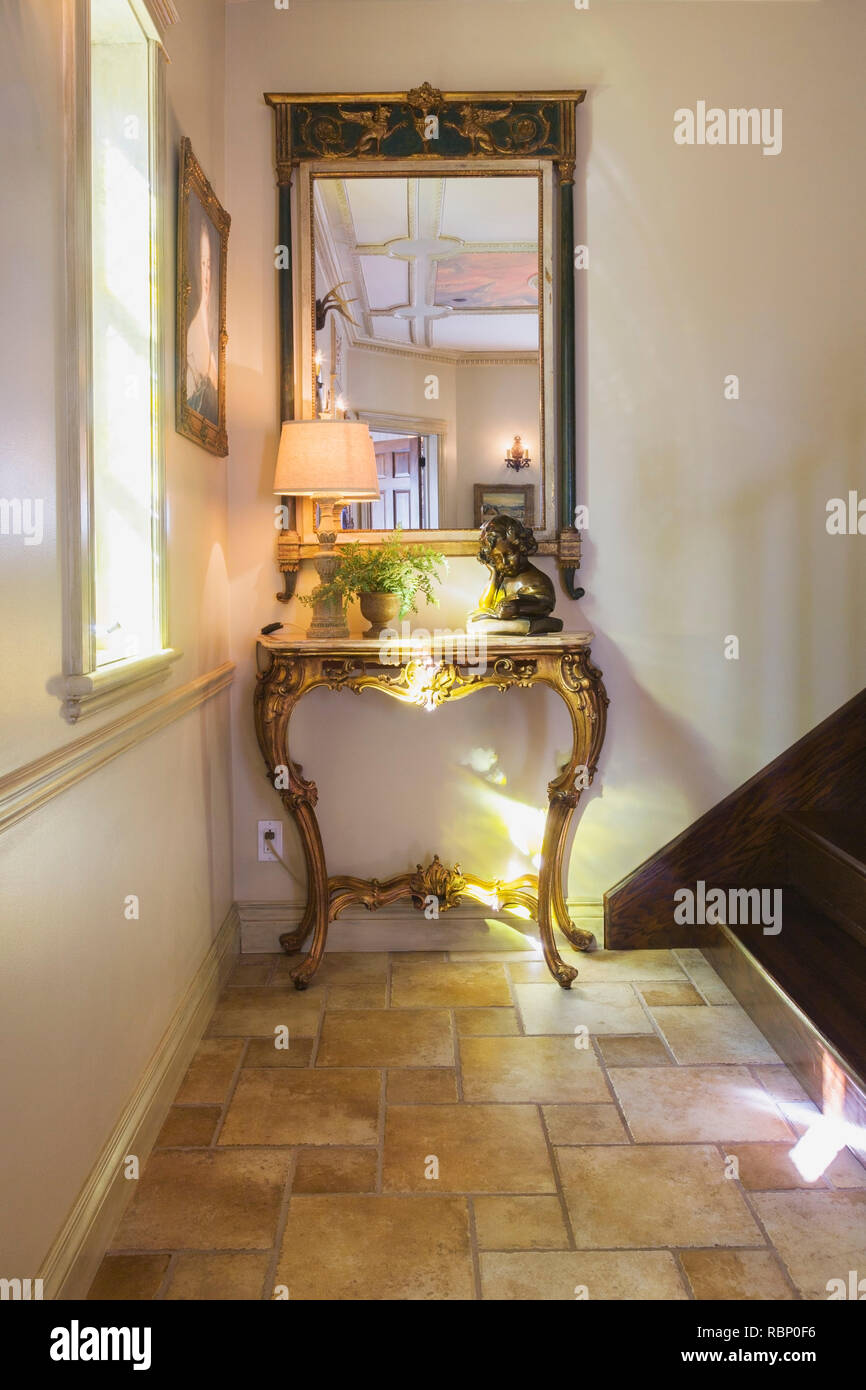 Antique wooden console with statue and illuminated lamp in main ...