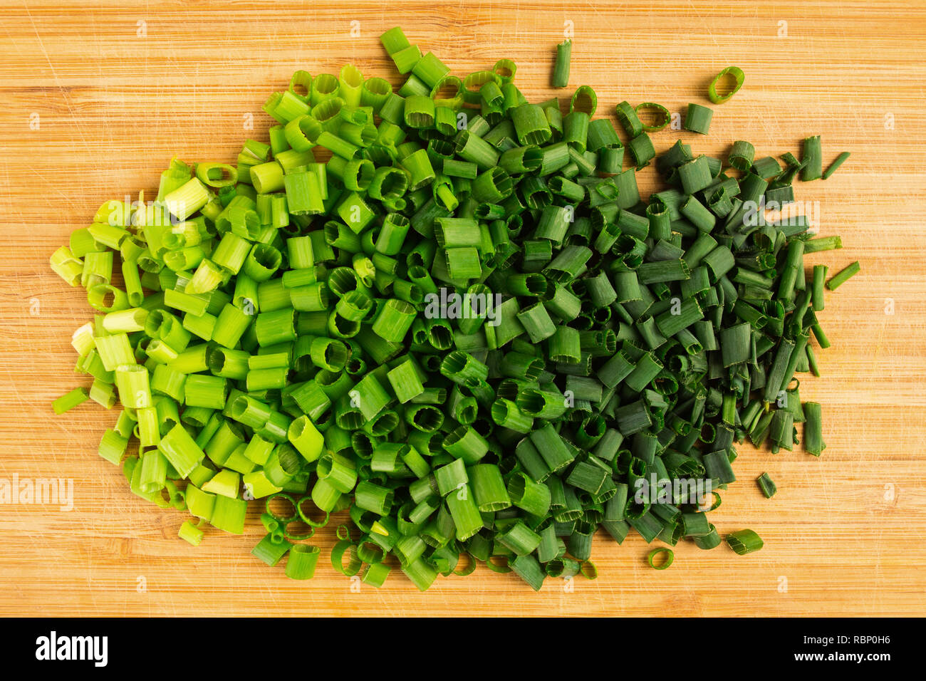 Chopped spring onion on the wooden board, green color gradation ...