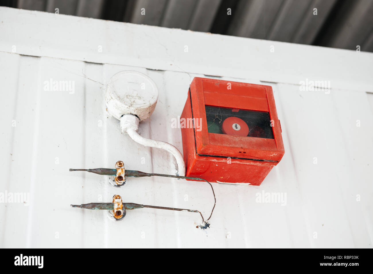 Alarm setting on the wall with two steel pipes and red cage with key ...