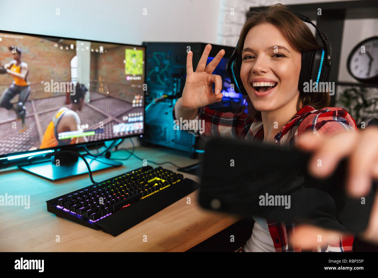 Excited girl gamer sitting at the table, playing online games on a ...