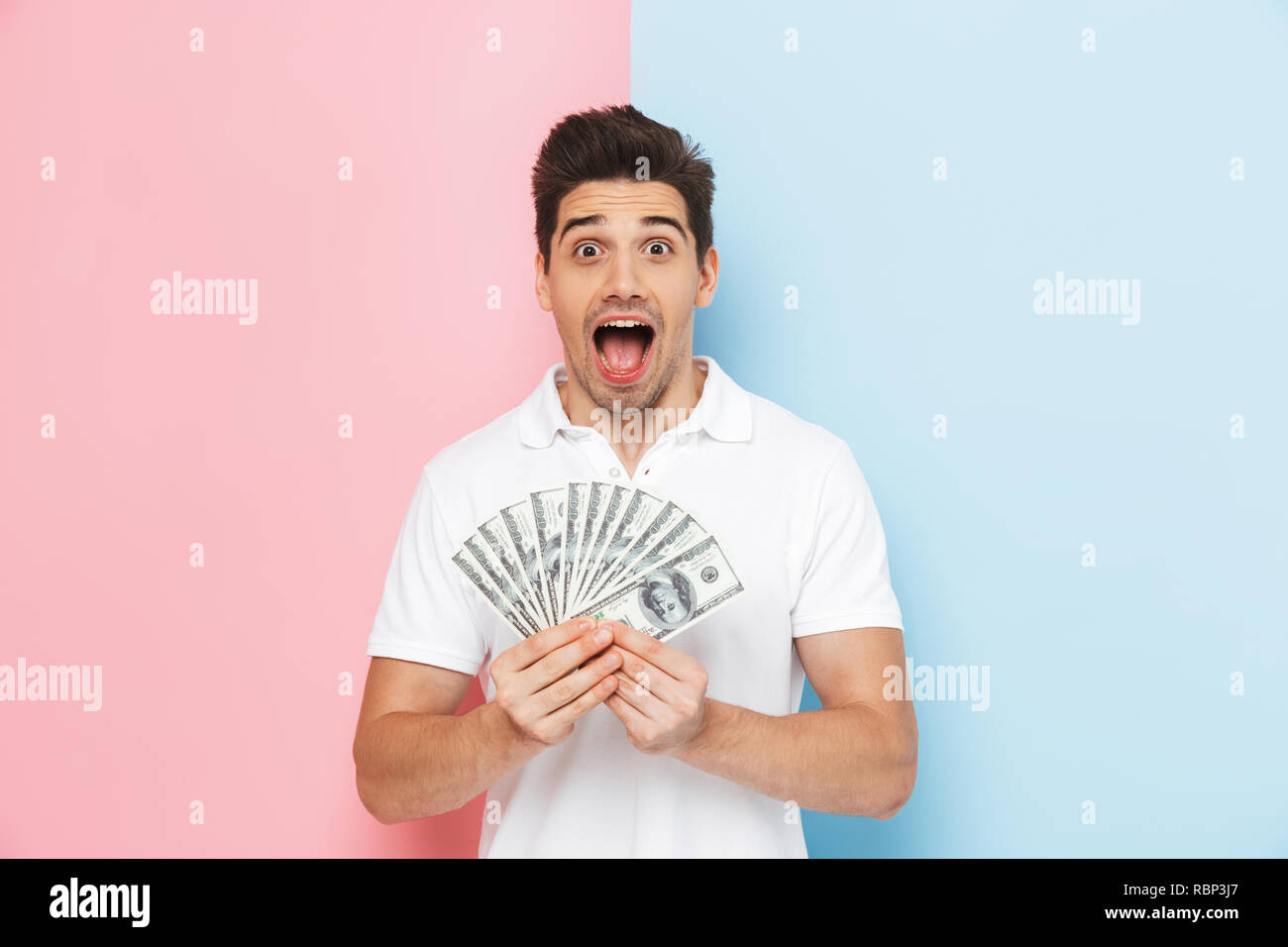 Smiling young man standing isolated over two colored background ...