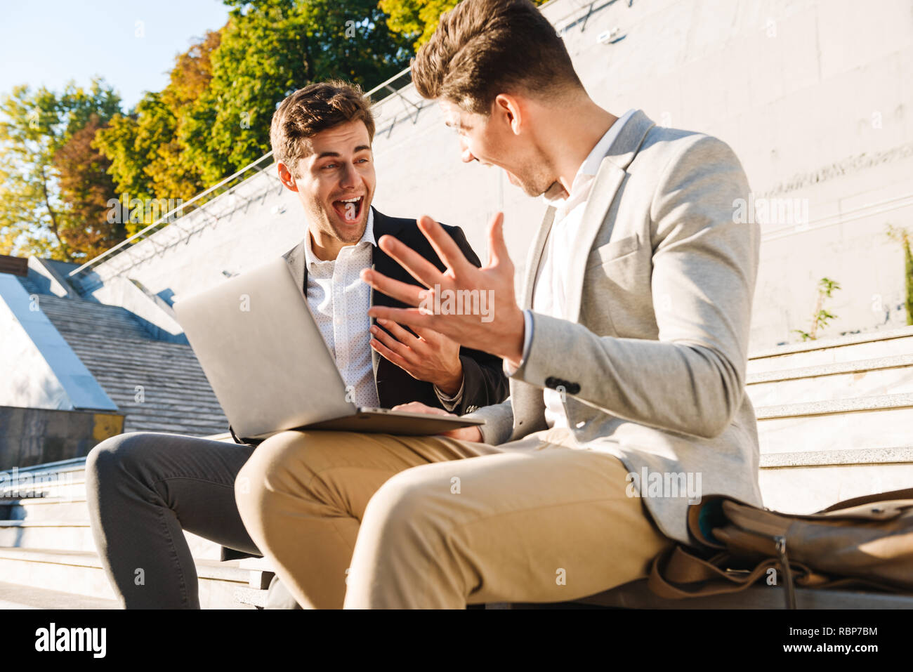 Two confident businessmen using laptop computer while sitting on a ...