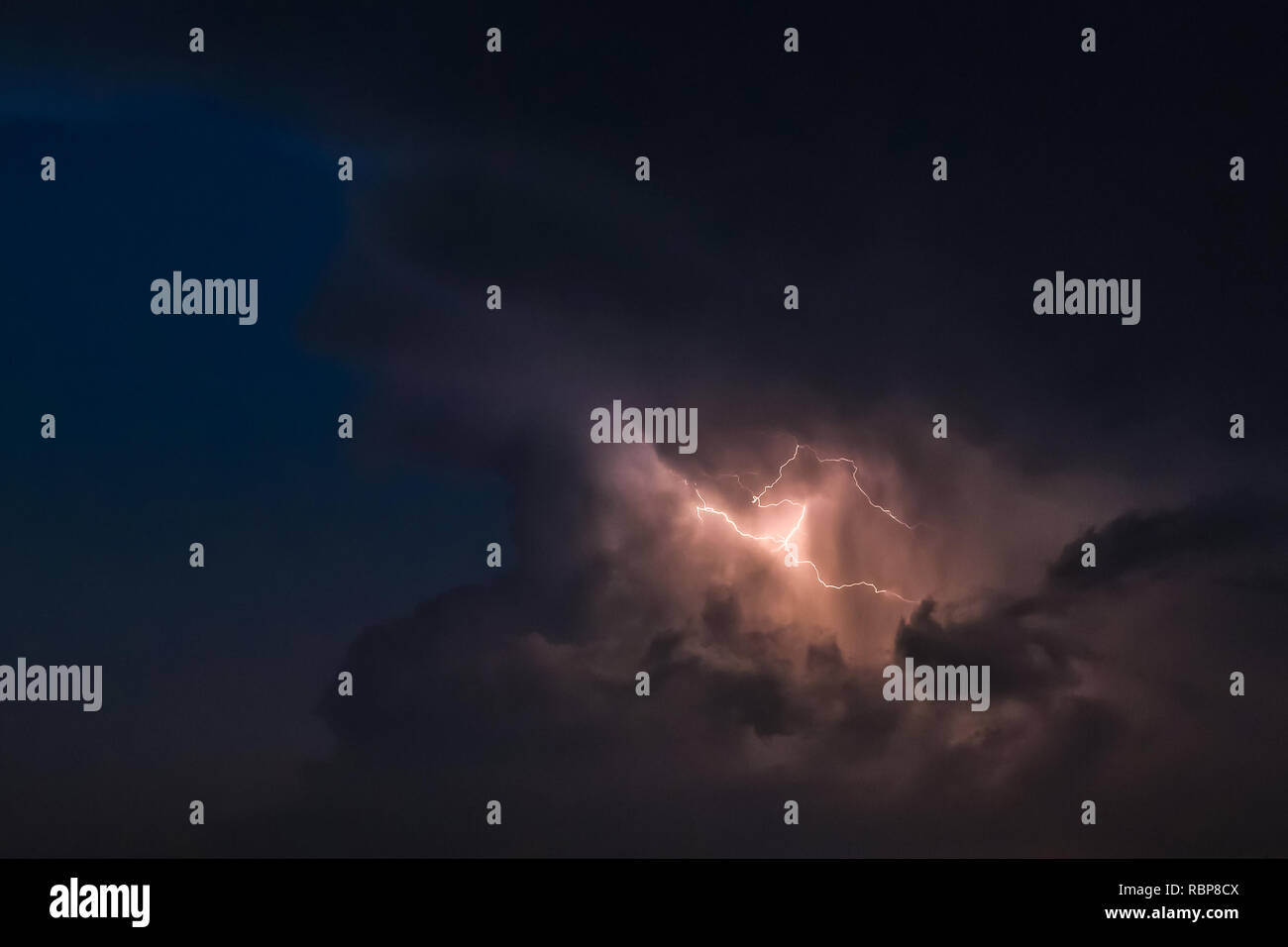 flash of lightning on a heavy cloudy background bringing thunder bolts ...