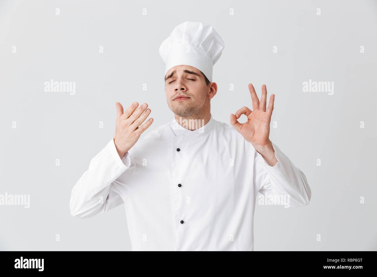 Cheerful chef cook wearing uniform tasting the smell isolated over ...