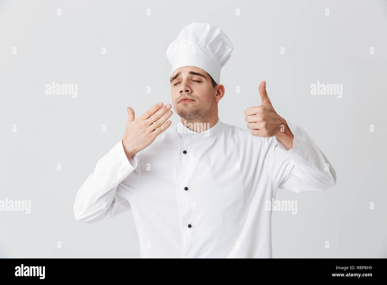 Cheerful chef cook wearing uniform tasting the smell isolated over ...
