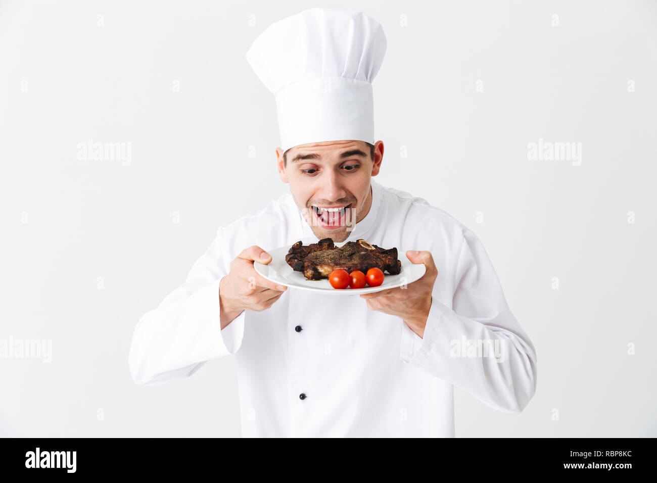 Cheerful chef cook wearing uniform peppers cooked beef steak meal on a ...