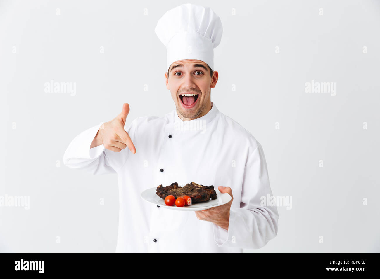 Cheerful chef cook wearing uniform peppers cooked beef steak meal on a ...