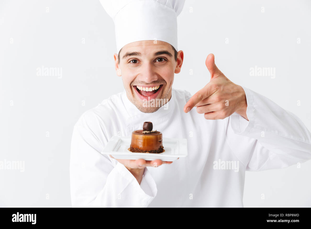 Cheerful man chef cook wearing uniform showing pastry on a plate ...