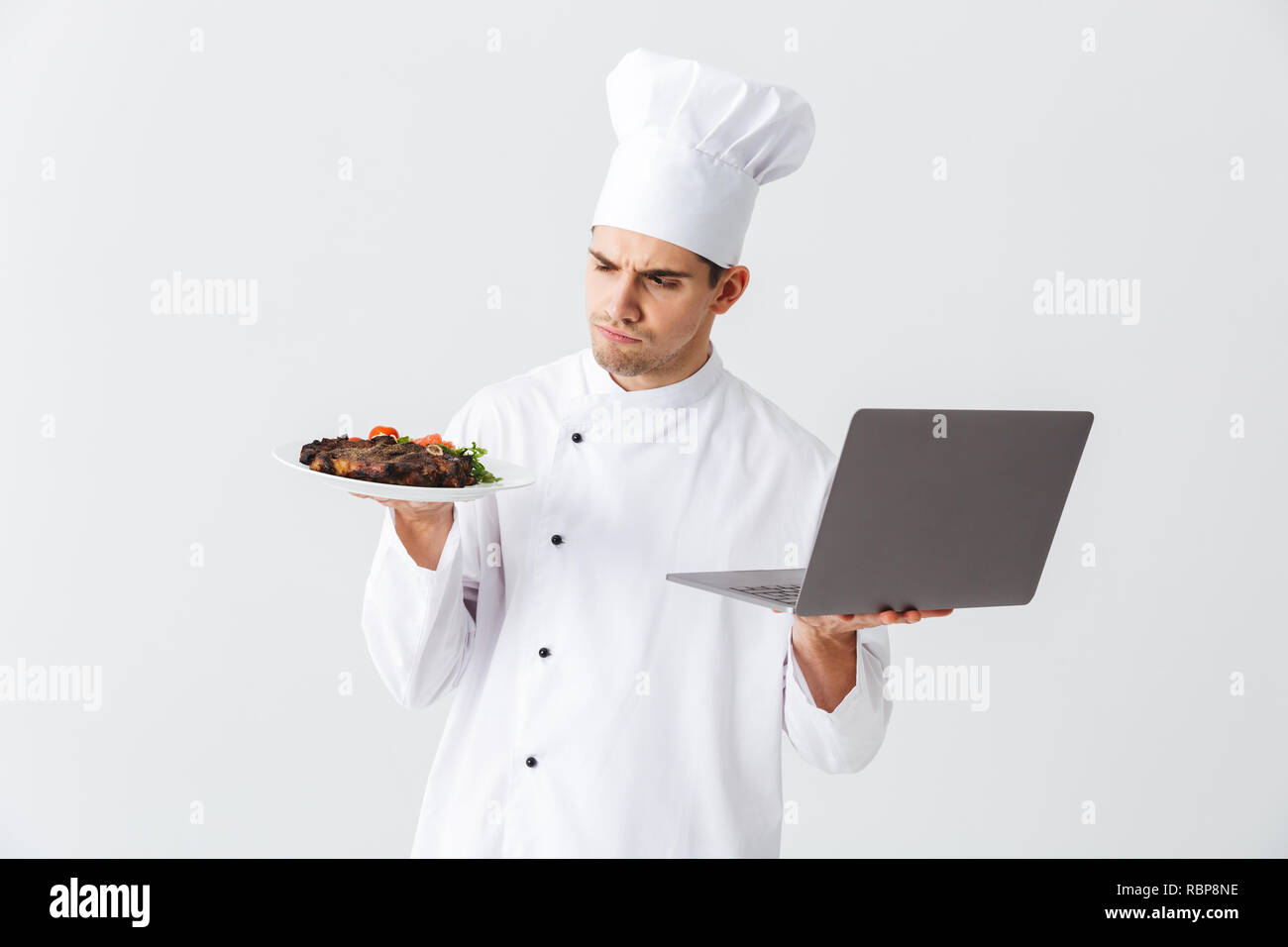 Serious chef cook wearing uniform standing over white background ...