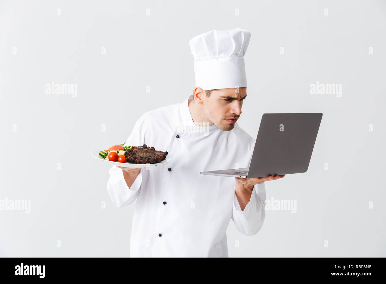 Serious chef cook wearing uniform standing over white background ...