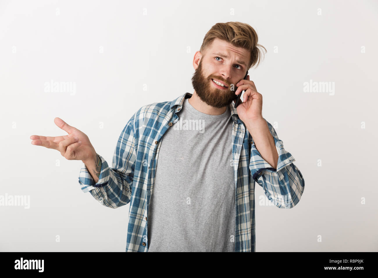 Picture of a confused young bearded man standing isolated over white ...
