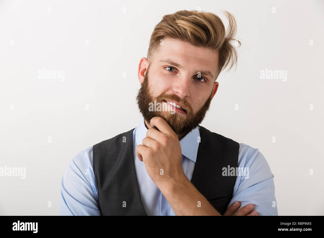 Image of a handsome young bearded man standing isolated over white wall ...