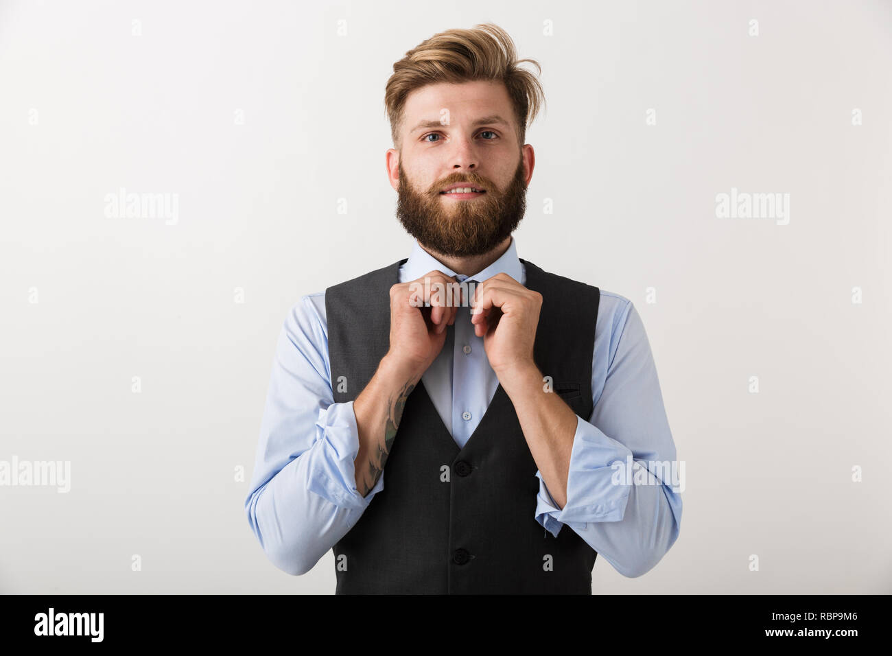Image of a handsome young bearded man standing isolated over white wall ...