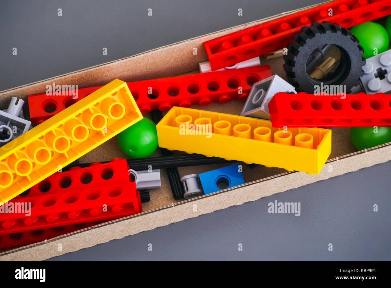 Color plastic blocks, bricks, tire and balls in paper box. Gray ...